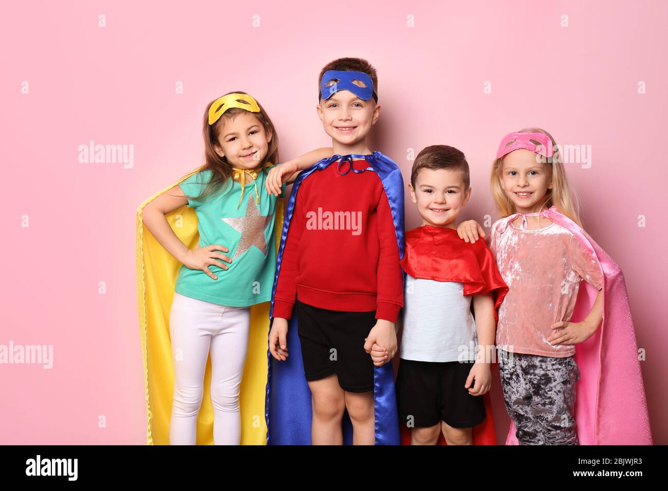 Cute children in superhero costumes on color background Stock Photo - Alamy