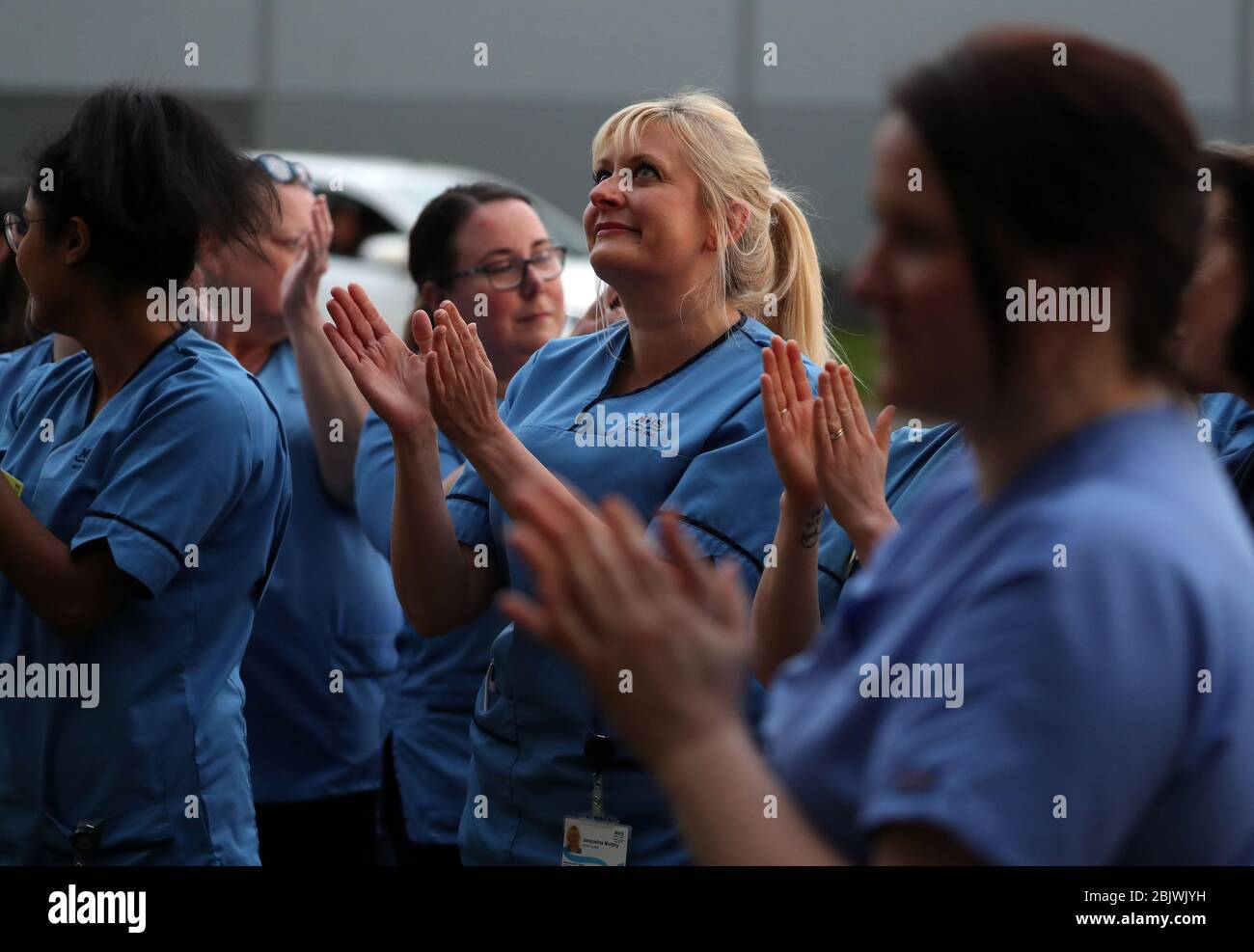 Nursing staff clap towards their colleagues as they look out from a ...