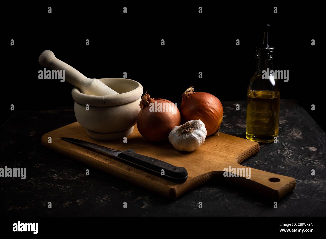 cooking scene with mortar, garlic, onions, knife and cutting board ...