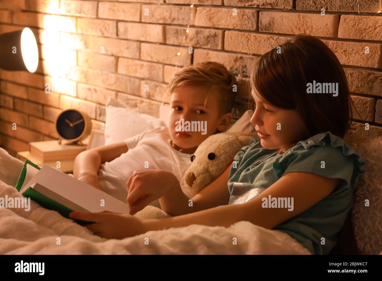 Cute little brother and sister reading bedtime story in evening Stock ...