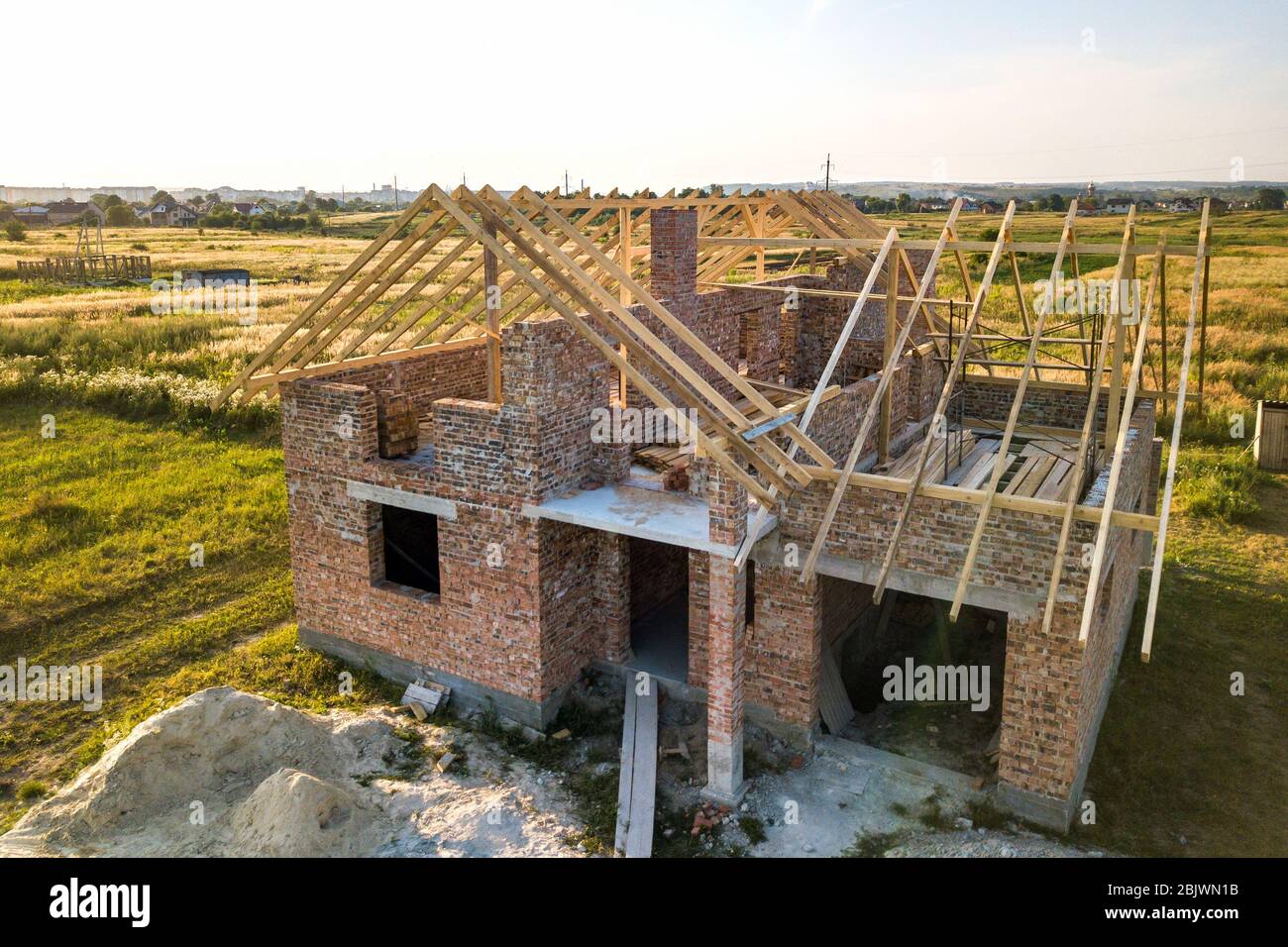 Unfinished brick house with wooden roof structure under construction ...