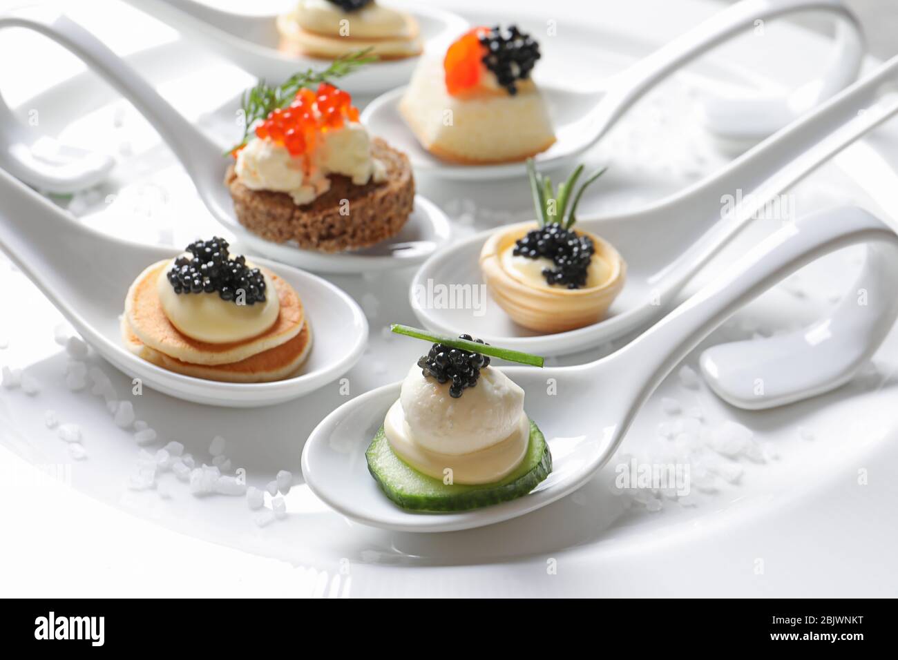 Spoons of canapes with black caviar on plate Stock Photo - Alamy