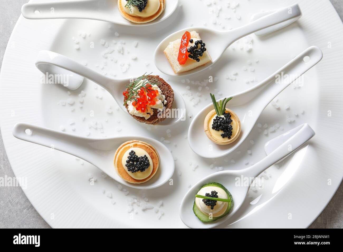 Spoons of canapes with black and red caviar on plate Stock Photo - Alamy