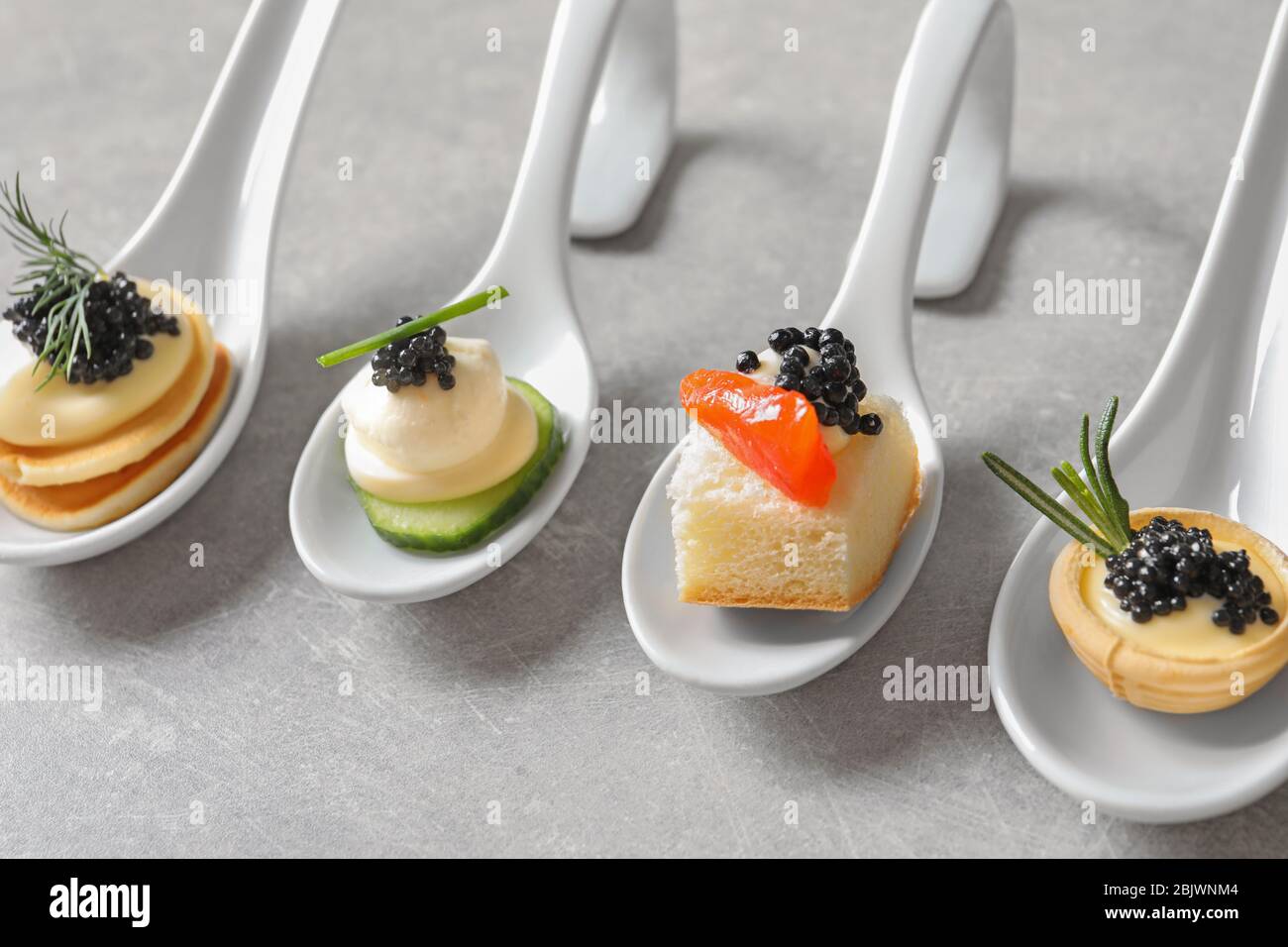 Spoons of canapes with black caviar on table Stock Photo - Alamy