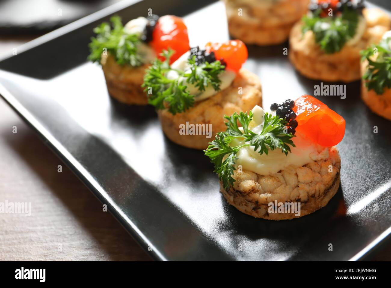 Delicious canapes with black caviar on plate, closeup Stock Photo - Alamy