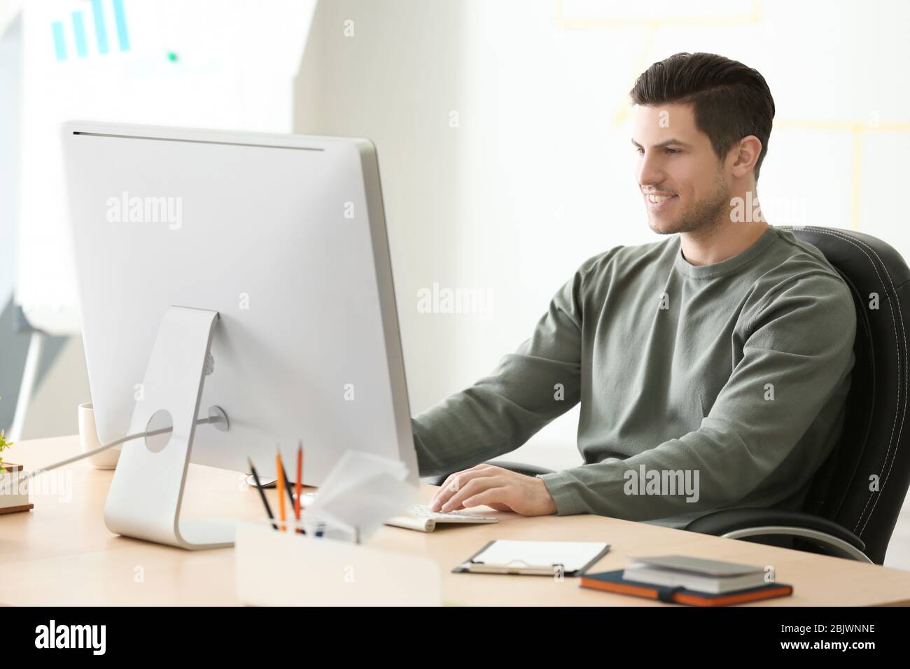 Young man working with computer at table in office Stock Photo - Alamy