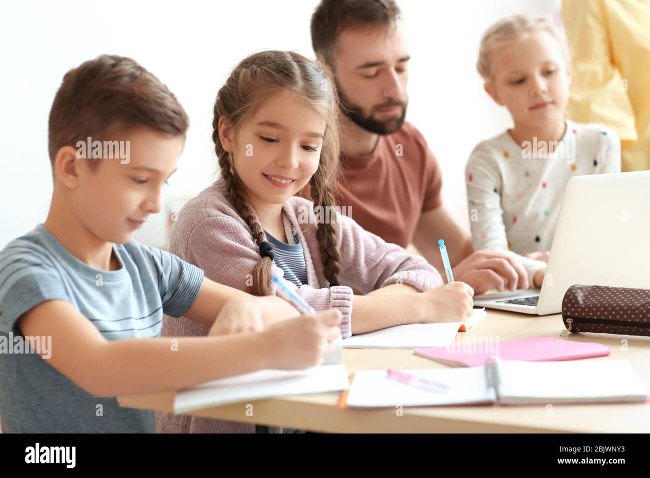 Children doing homework with teacher in classroom at school Stock Photo ...
