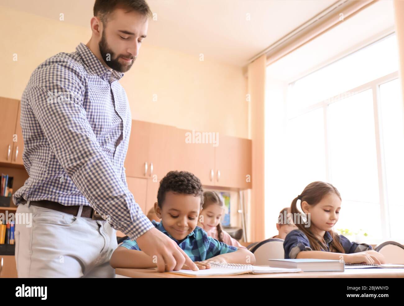 Male teacher helping boy with his homework in classroom at school Stock ...