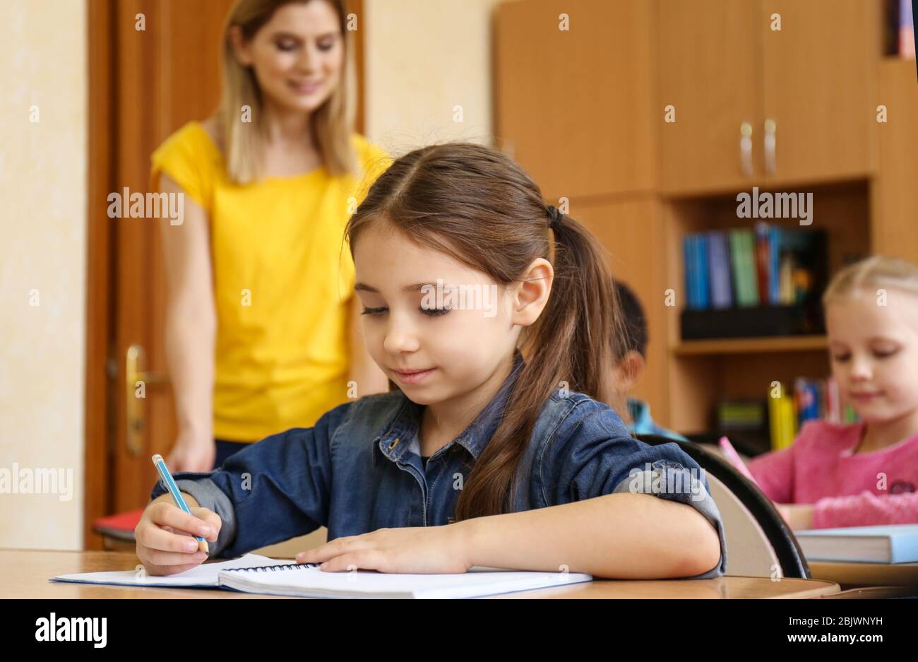 Cute girl doing homework in classroom at school Stock Photo - Alamy