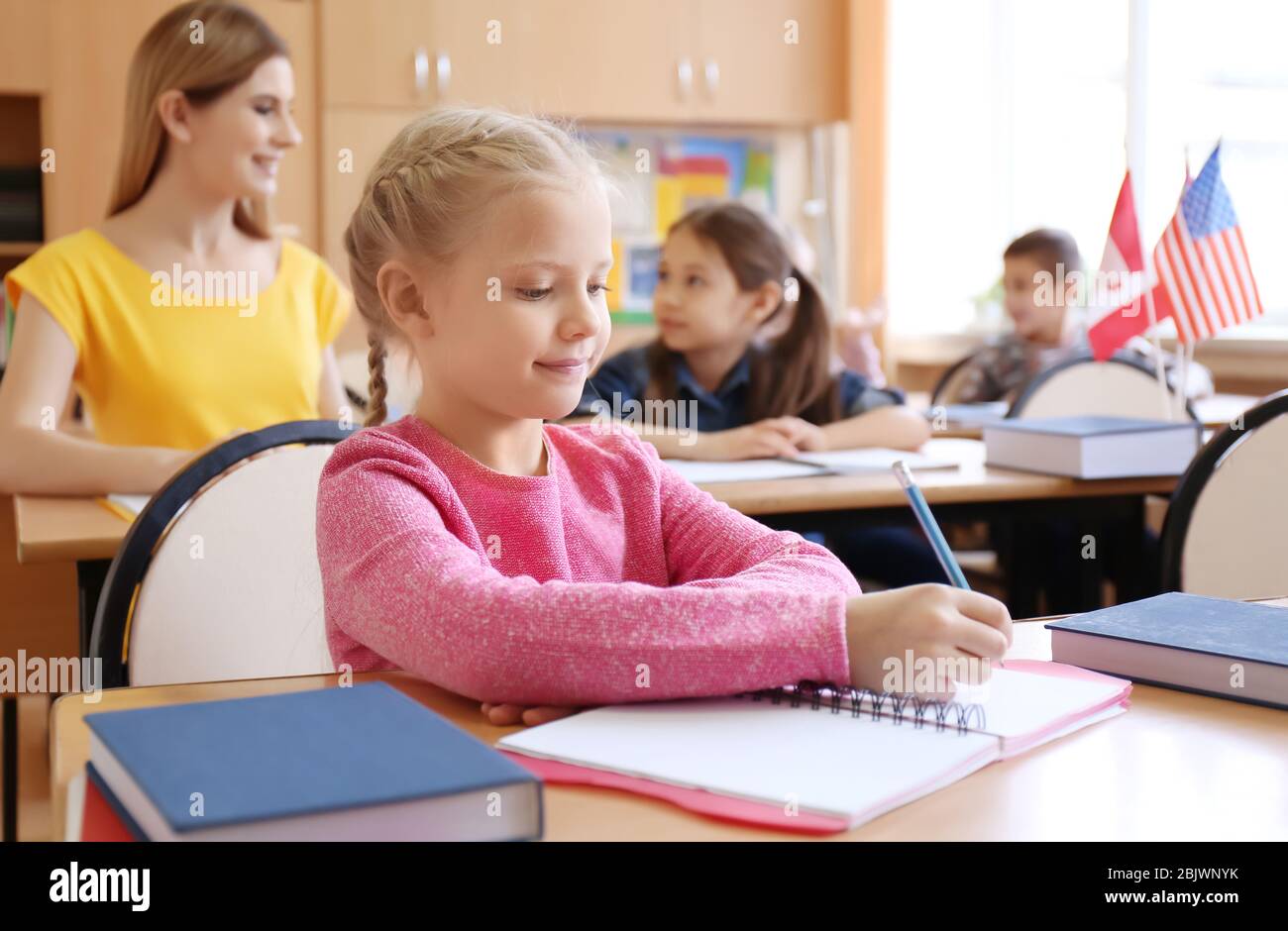 Cute girl doing homework in classroom at school Stock Photo - Alamy