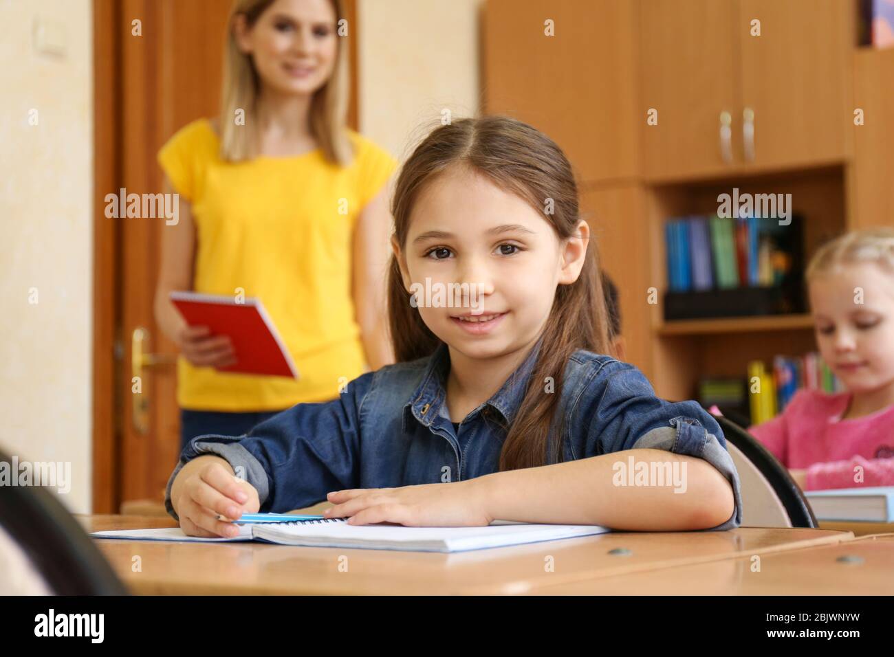 Cute girl doing homework in classroom at school Stock Photo - Alamy