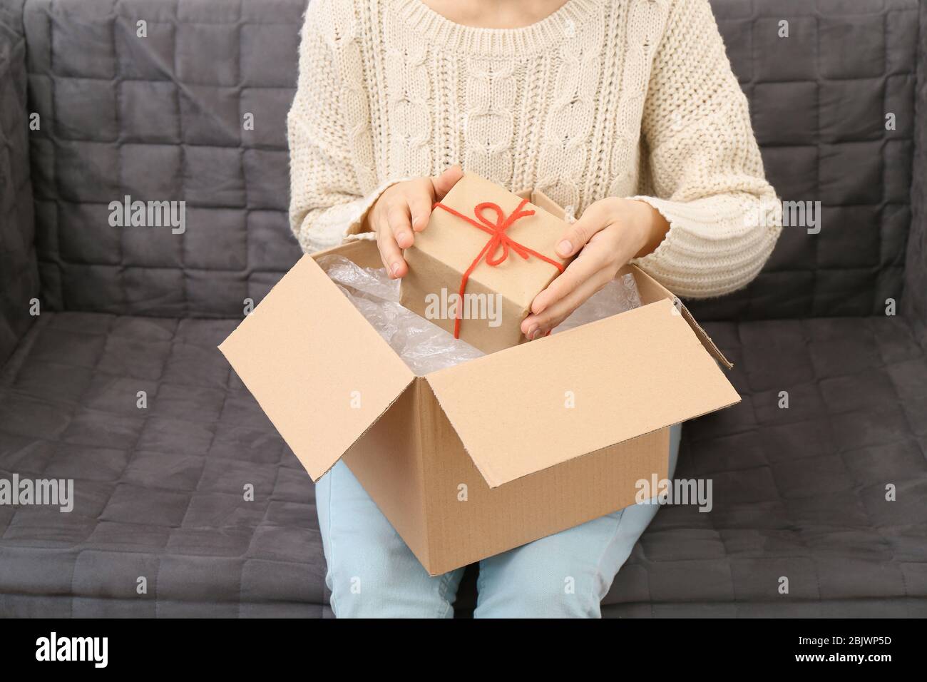 Woman taking gift box out of parcel at home Stock Photo - Alamy