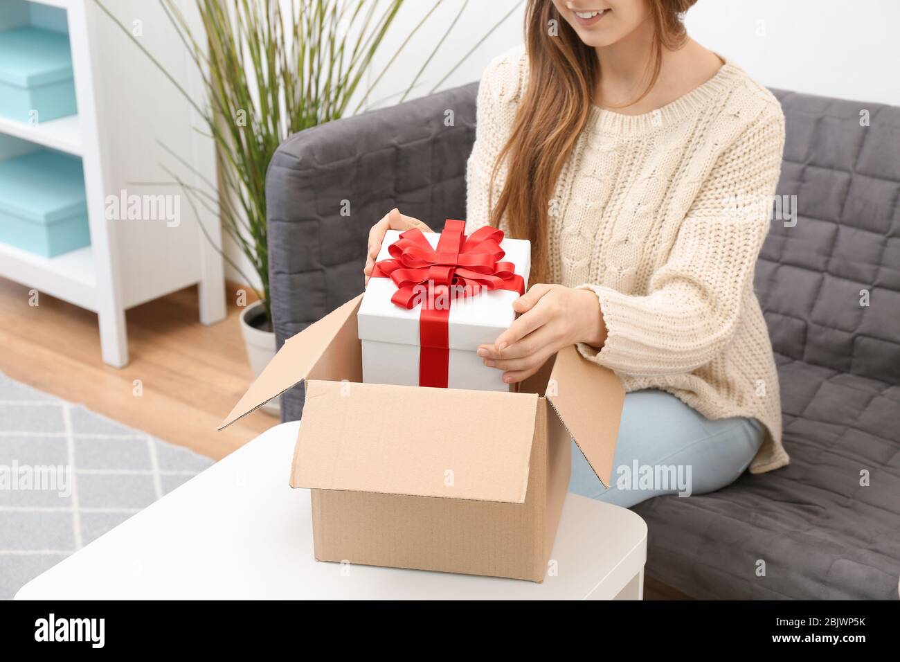 Woman taking gift box out of parcel at home Stock Photo - Alamy