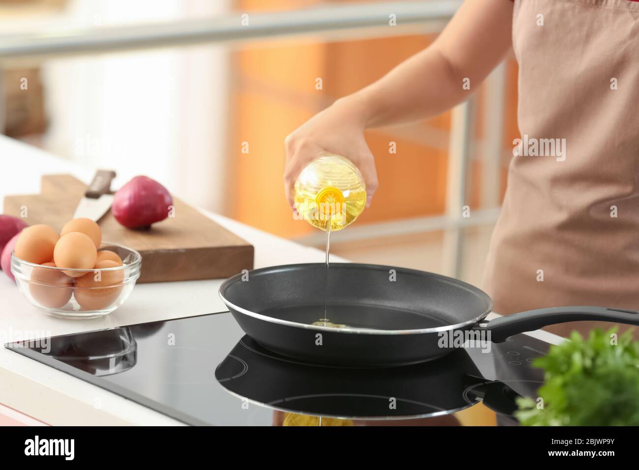 Woman pouring cooking oil from bottle into frying pan on stove Stock ...