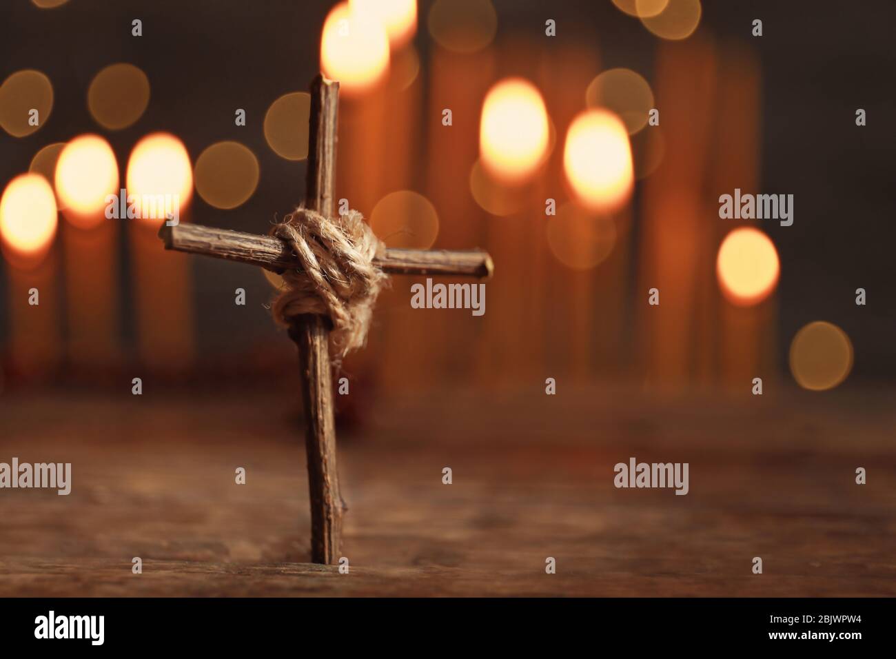 Wooden cross on table against defocused lights Stock Photo - Alamy