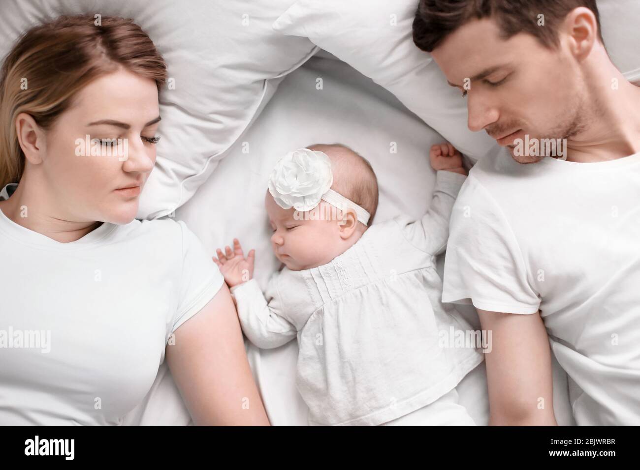 Young parents with baby sleeping on bed at home Stock Photo - Alamy