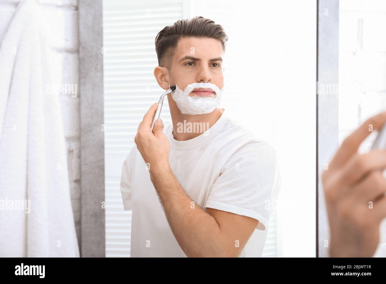 Handsome man shaving in bathroom Stock Photo - Alamy