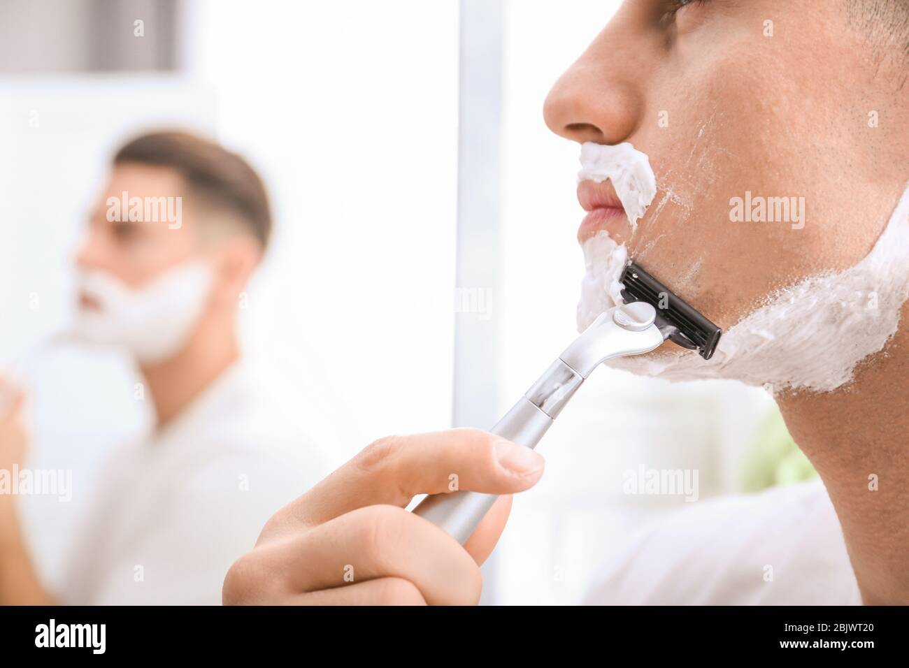 Handsome man shaving in bathroom Stock Photo - Alamy