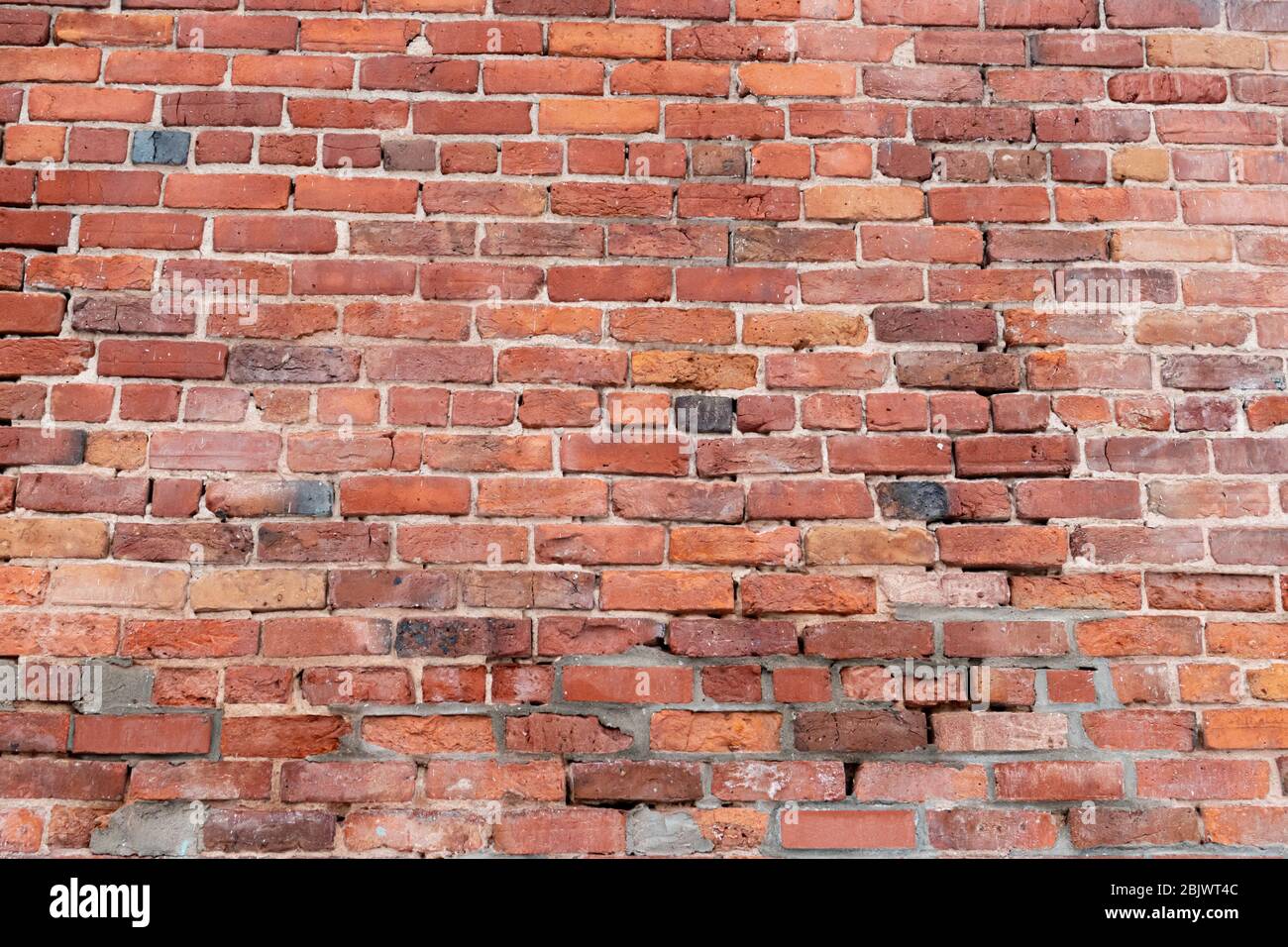An old wall of red bricks with several parts of the masonry showing ...
