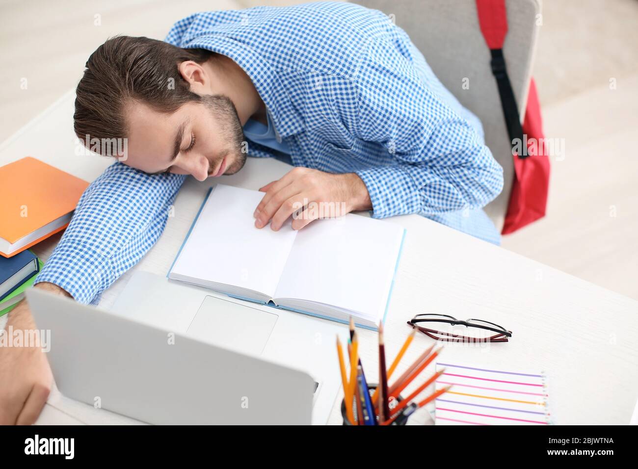 Tired student sleeping at table indoors Stock Photo - Alamy