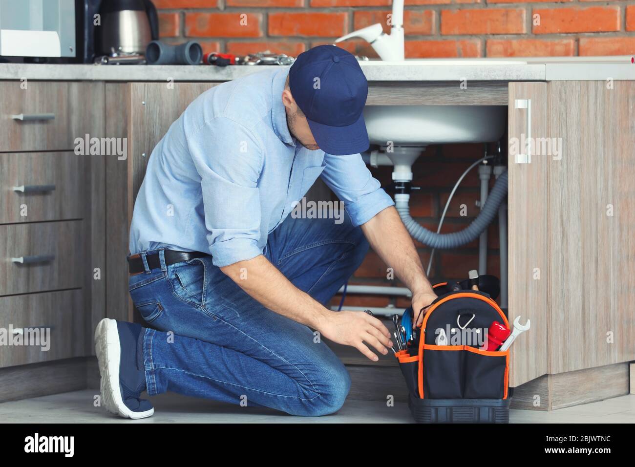 Professional plumber fixing kitchen sink Stock Photo - Alamy