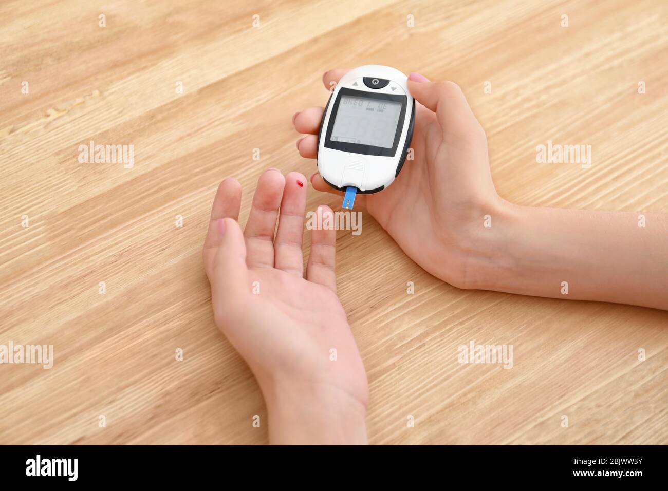 Diabetic woman using digital glucometer over table Stock Photo - Alamy