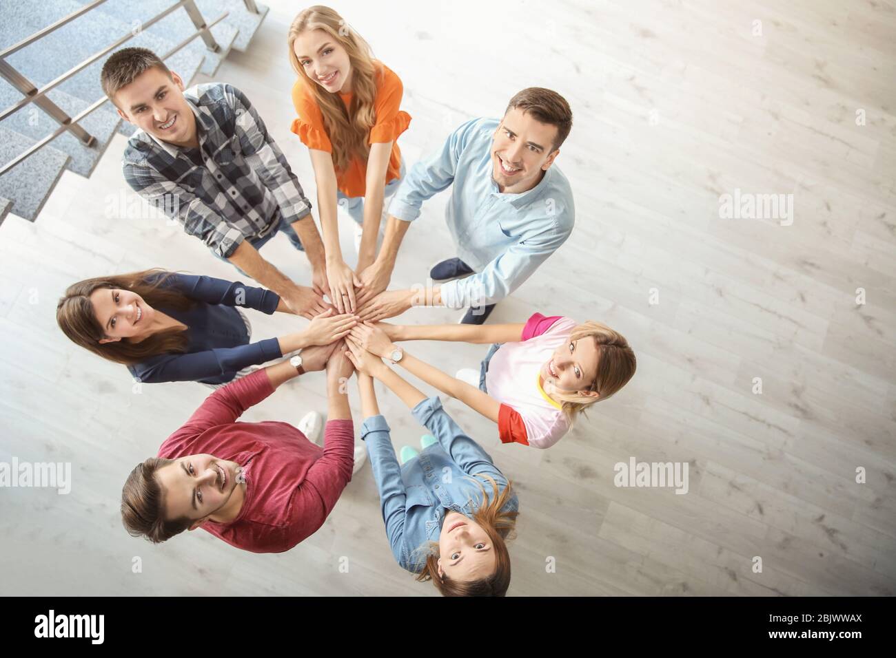Young people putting hands together indoors. Unity concept Stock Photo ...