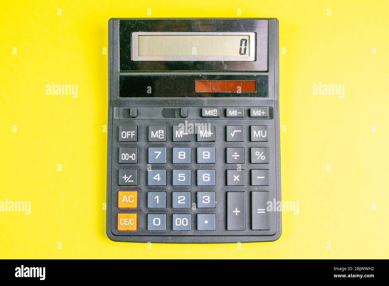 Black calculator on yellow background. Top view Stock Photo - Alamy