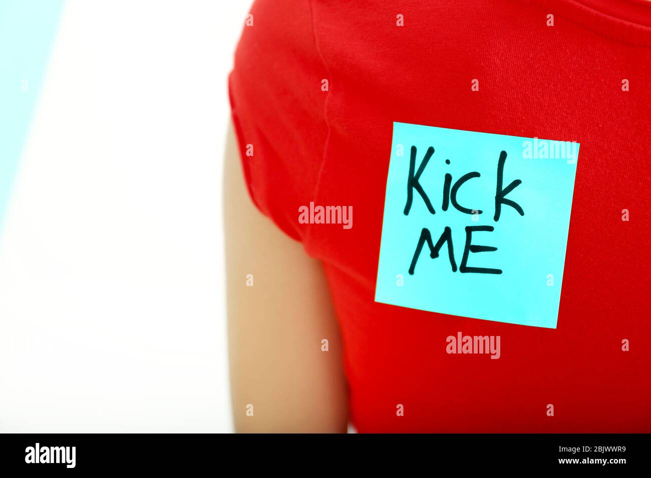 Sticky note with phrase "Kick me" on woman's back, closeup. April fool ...