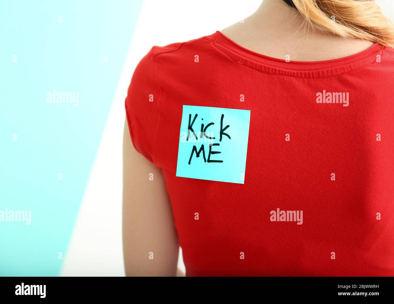 Sticky note with phrase "Kick me" on woman's back, closeup. April fool ...