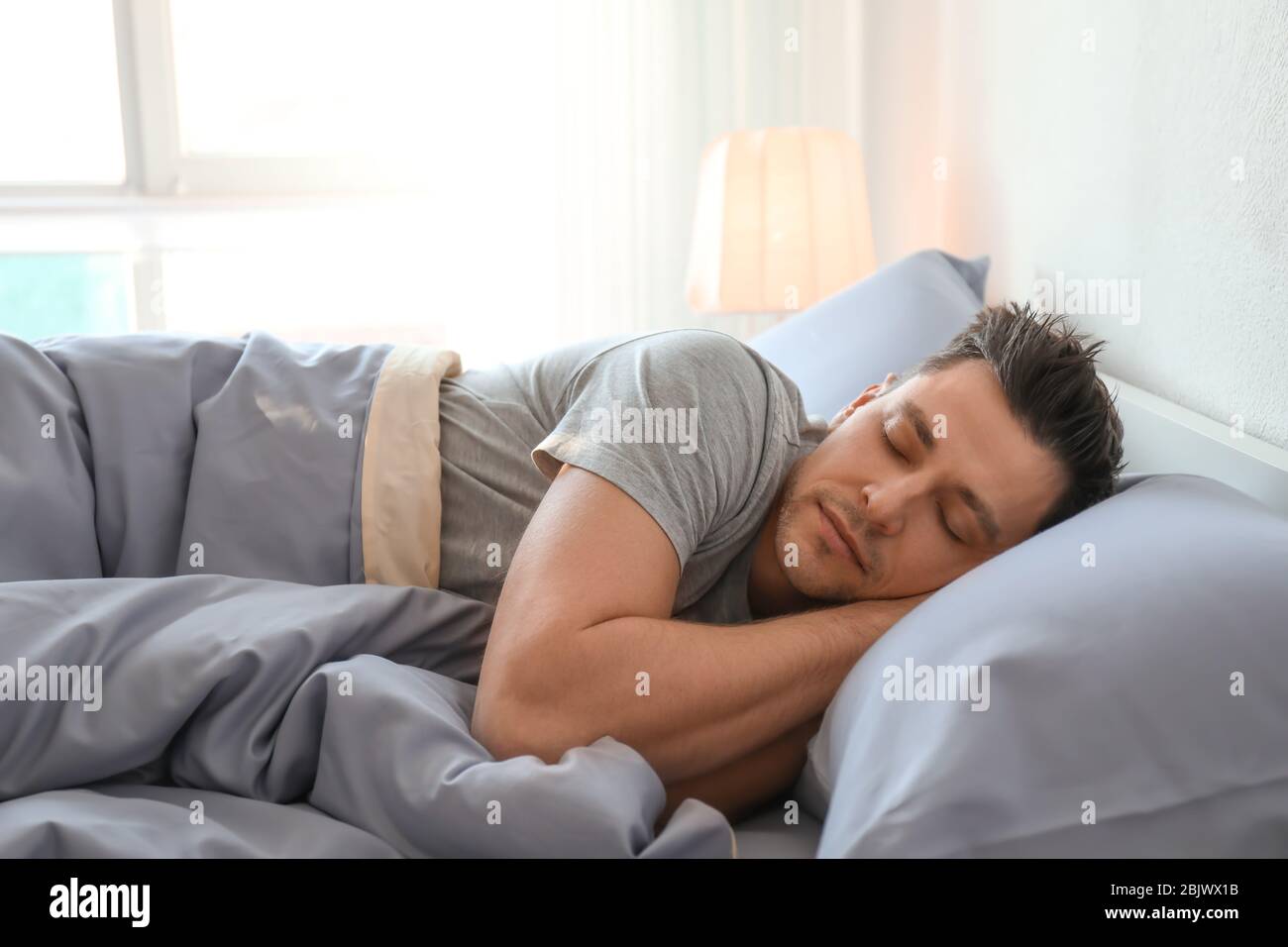 Young man sleeping in bed at home Stock Photo - Alamy