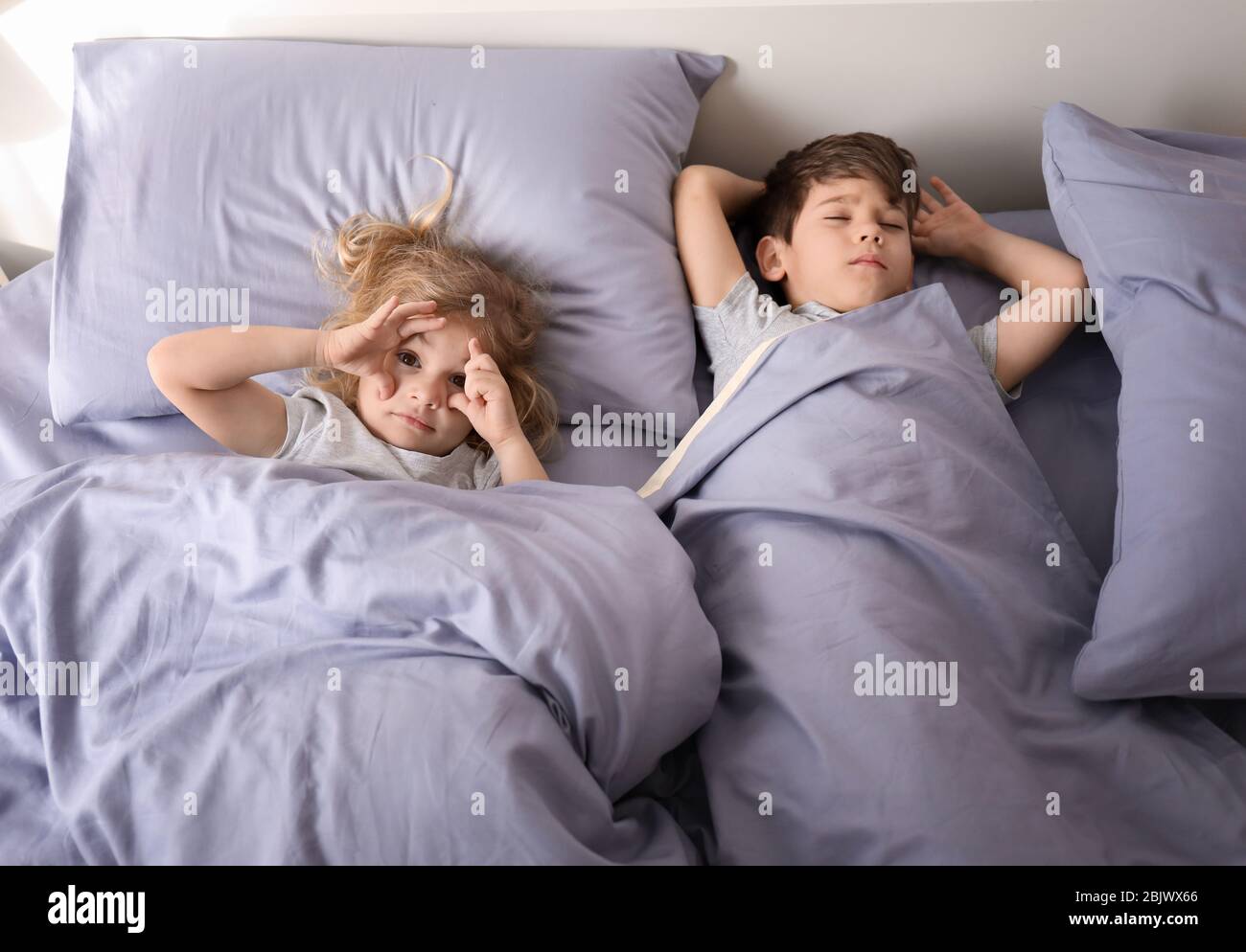 Cute Boy Sleeping While His Little Sister Trying To Fall Asleep In Bed