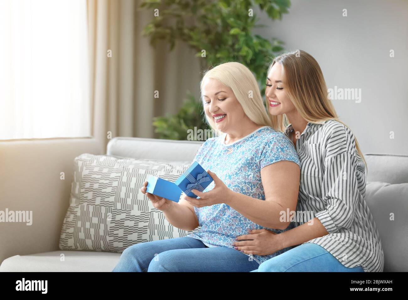 Young daughter giving gift box to mother at home Stock Photo - Alamy