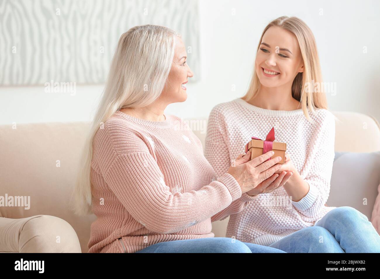 Young daughter giving gift box to mother at home Stock Photo - Alamy