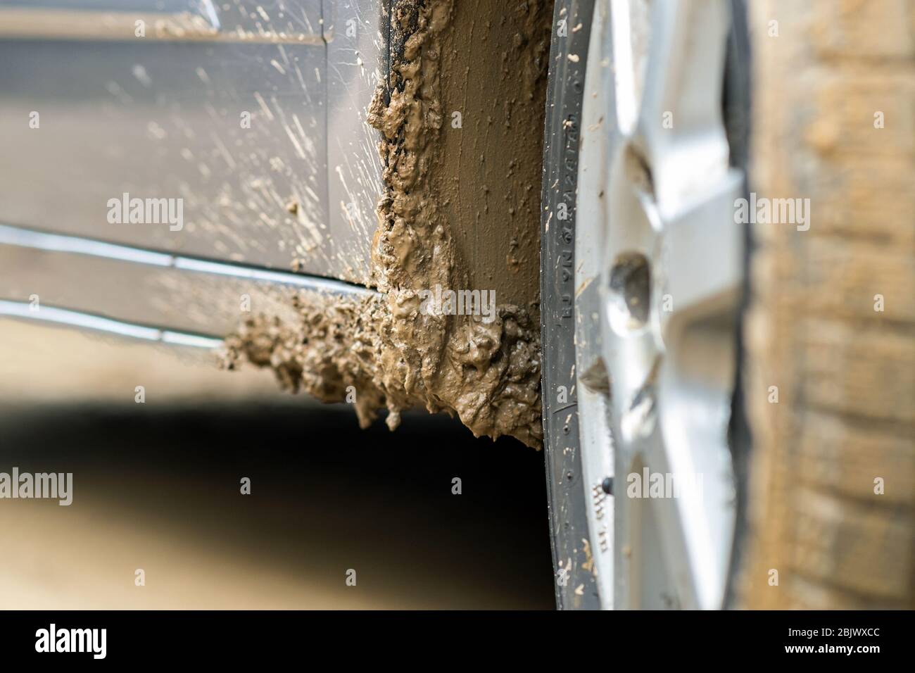 Close up of dirty car wheel with rubber tire covered with yellow mud ...