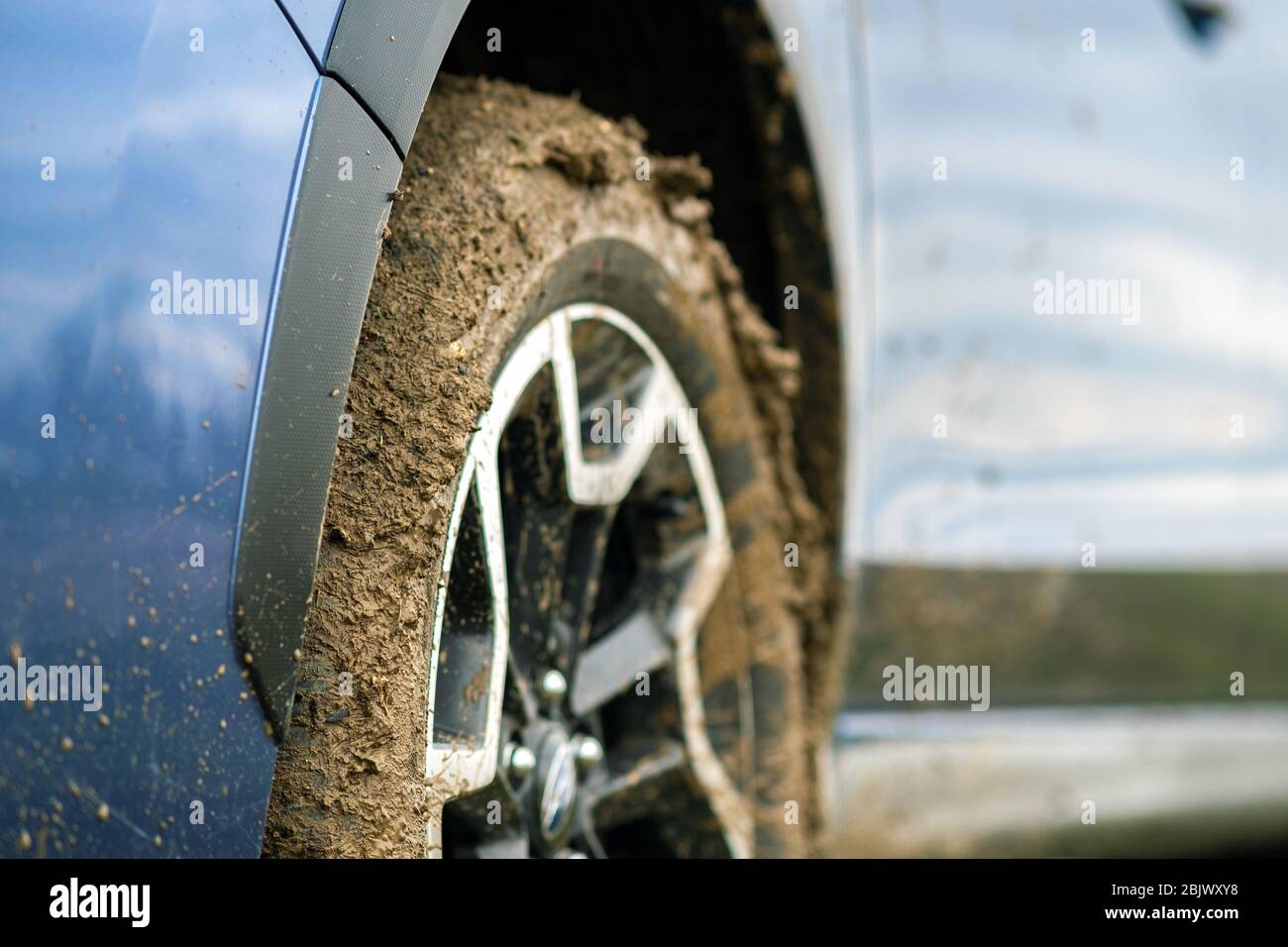 Close up of dirty car wheel with rubber tire covered with yellow mud ...