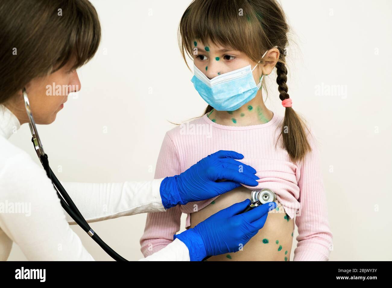 Doctor examining child girl covered with green rashes on face and ...