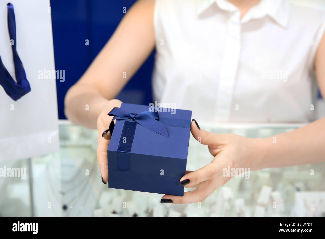 Young shop assistant with gift box and bag in jewelry store Stock Photo ...