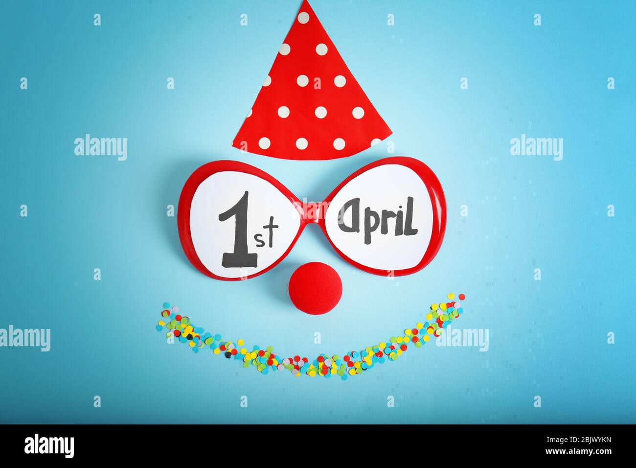 Clown nose, glasses and party cap on color background. April fool's day ...