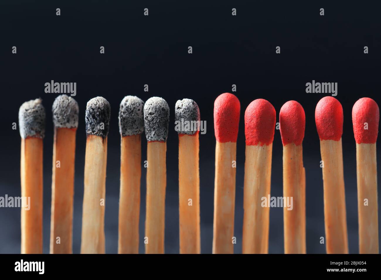 Group of burnt matches among others on black background. Difference and ...