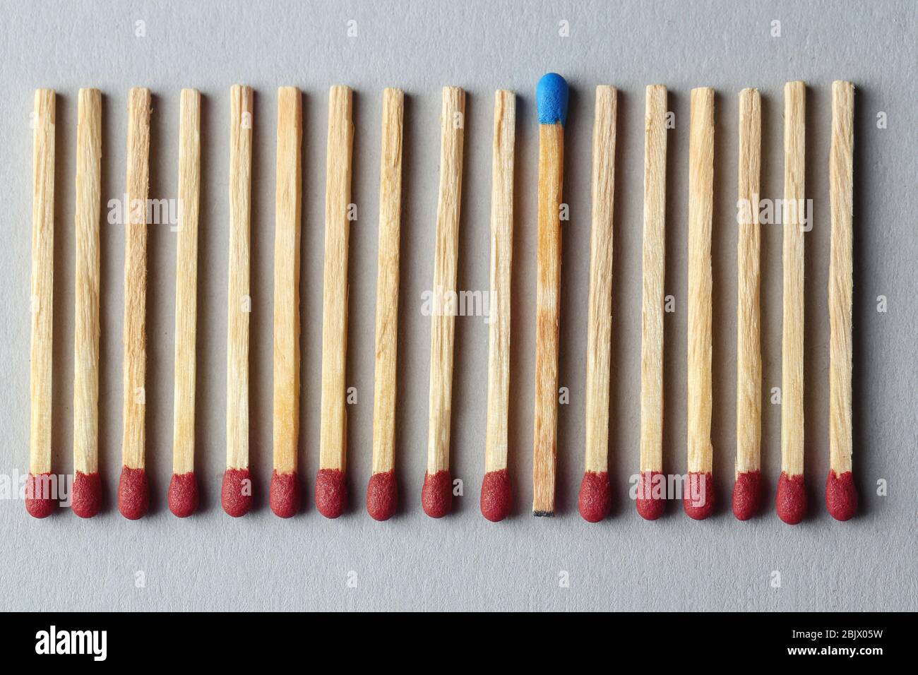 Blue match among brown ones on light background. Difference and ...