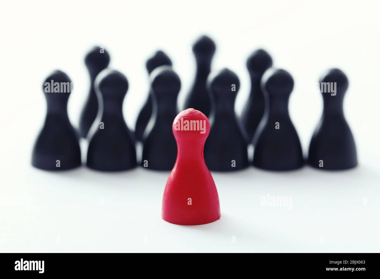 Red pawn in front of black ones on white background. Difference and ...