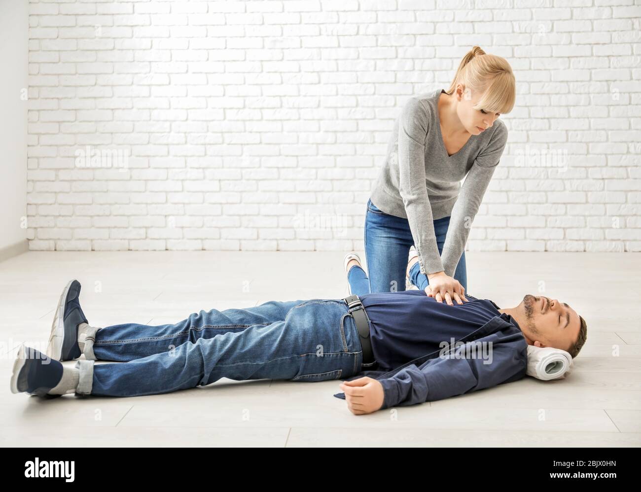 Young woman giving first aid to unconscious man on floor, indoors Stock ...