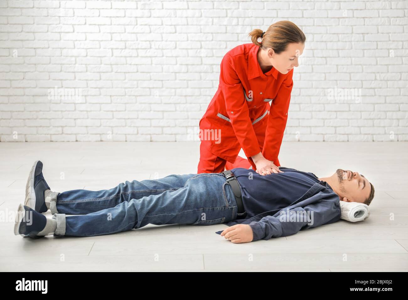 Young woman giving first aid to unconscious man on floor, indoors Stock ...