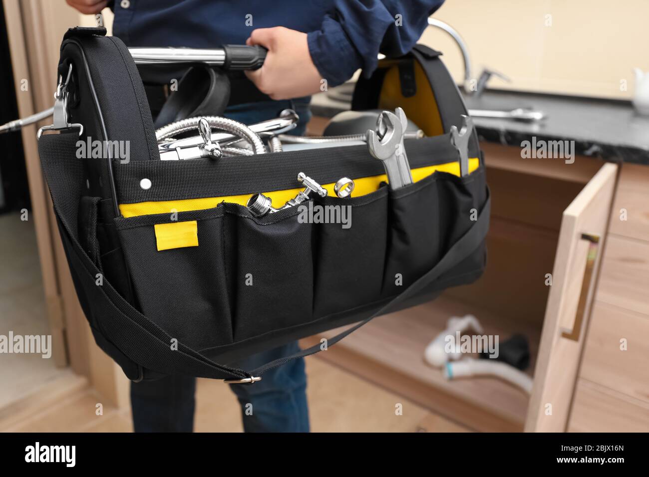 Plumber with set of tools in kitchen, closeup Stock Photo - Alamy