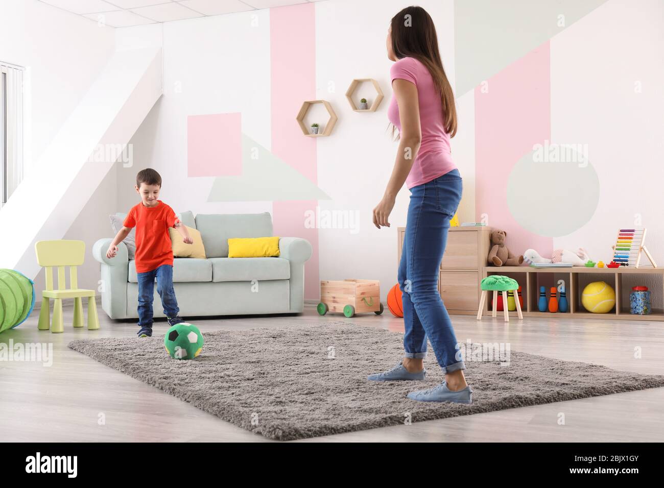 Nanny and little boy playing football at home Stock Photo - Alamy