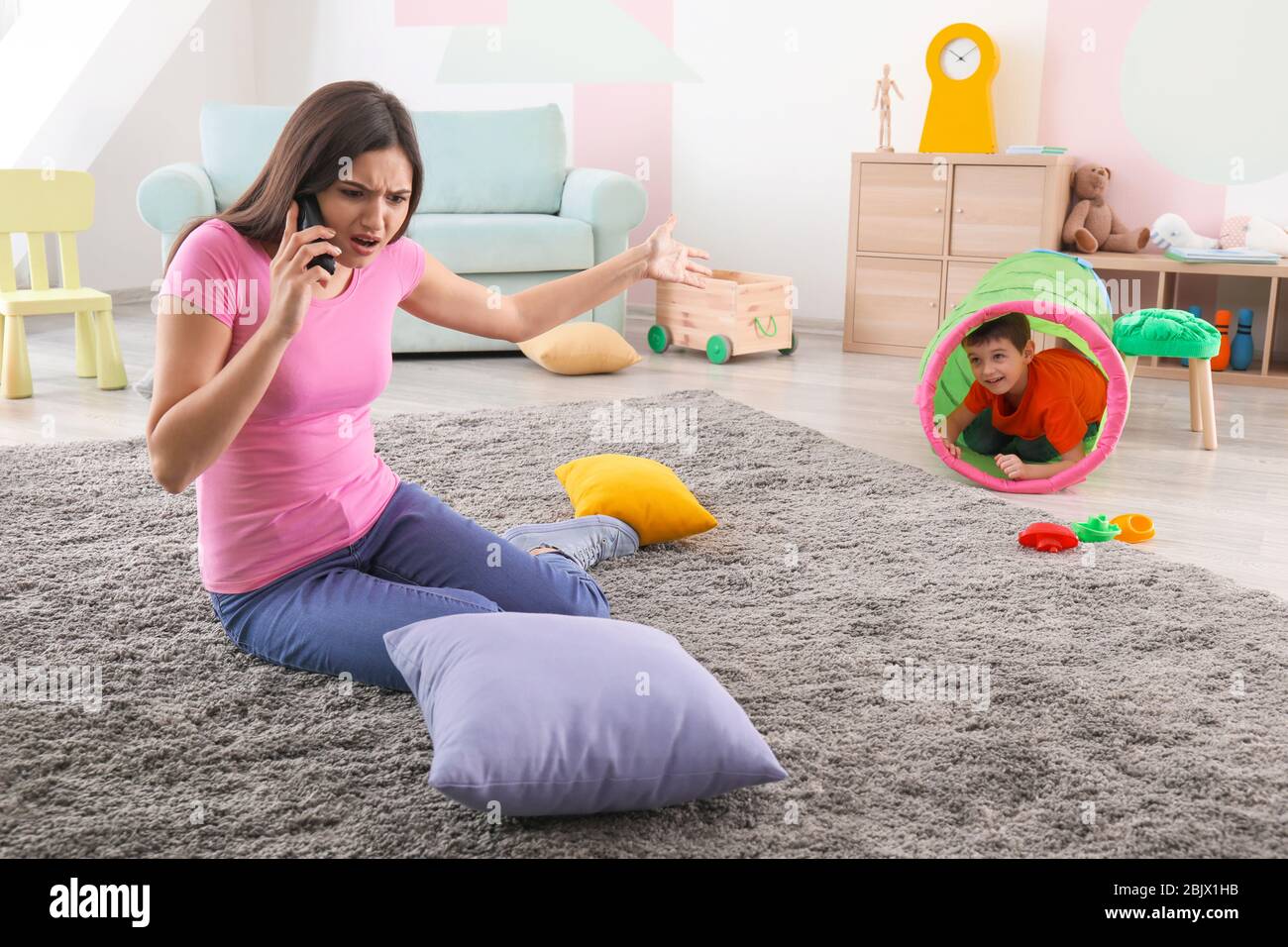 Playful little boy and annoyed nanny talking on phone at home Stock ...