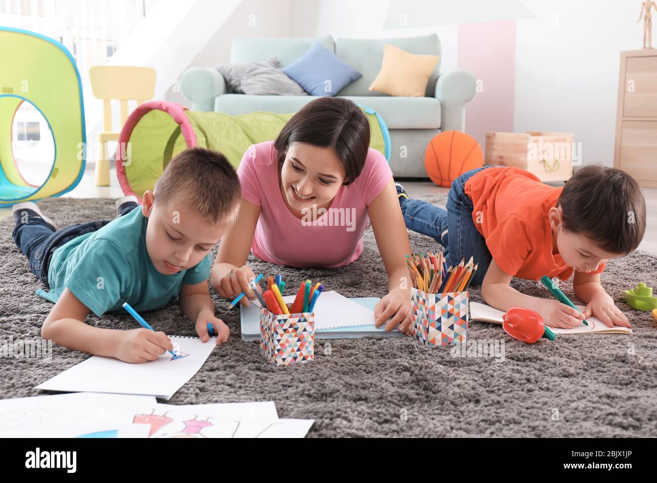 Two little boys drawing with nanny at home Stock Photo - Alamy