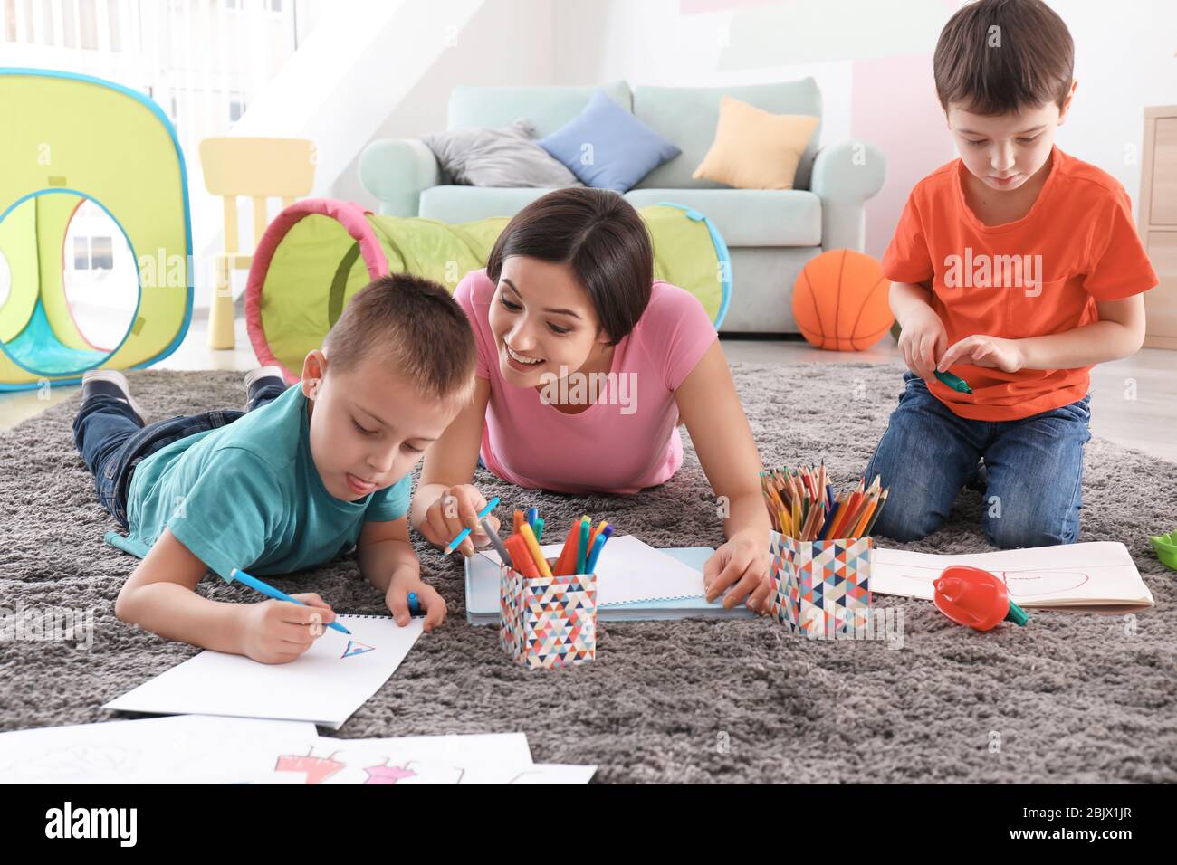 Two little boys drawing with nanny at home Stock Photo - Alamy
