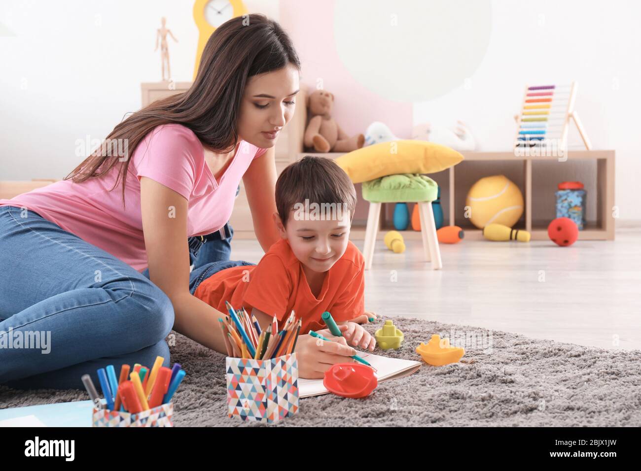 Little boy drawing with nanny at home Stock Photo - Alamy